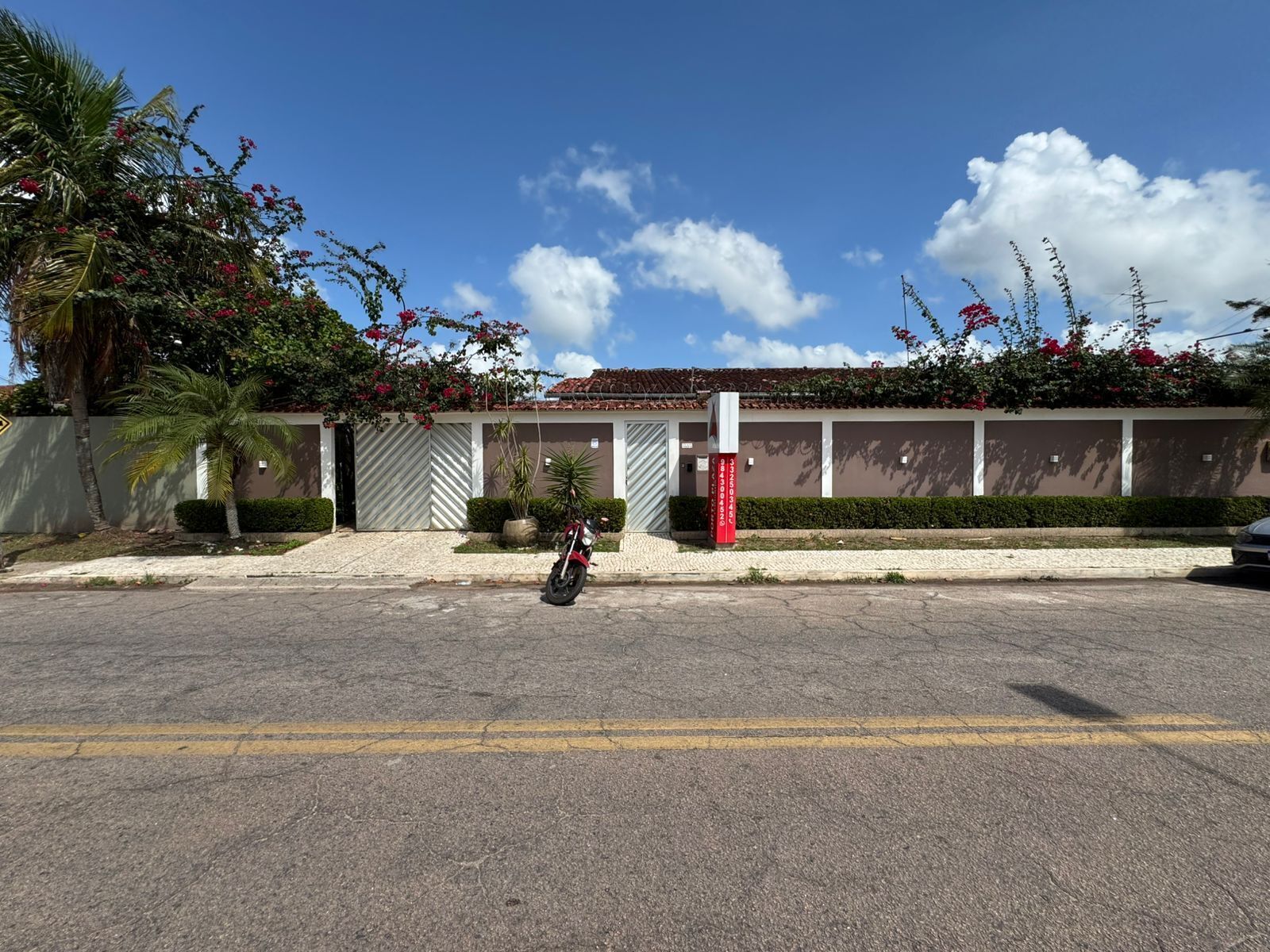 Um edifício com telhado de azulejos, uma motocicleta estacionada na frente, e um céu claro.