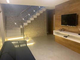 Uma sala de estar moderna com escada, TV de tela plana e estante embutida.