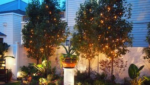 Um jardim com árvores, um cachepot e diversas plantas.