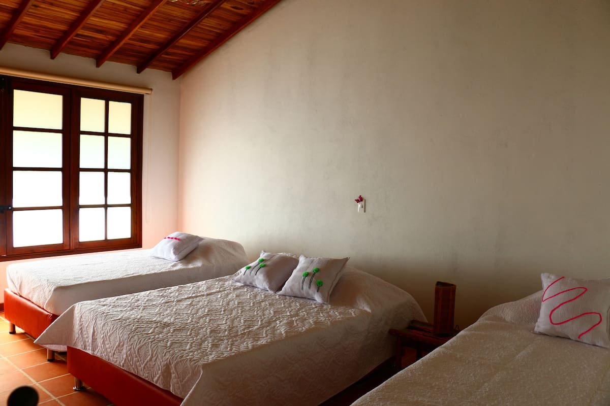 Quarto com duas camas, uma janela e teto de madeira.