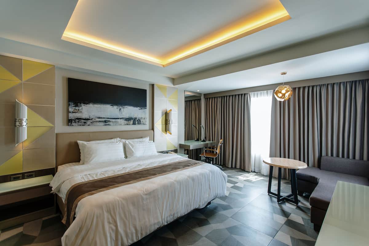 Quarto de hotel moderno com uma cama grande, uma escrivaninha, uma cadeira e vista para o exterior.