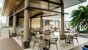 Uma área de terraço ao ar livre com piso de madeira, vários conjuntos de assentos e vista para a paisagem.