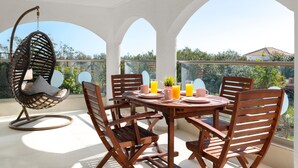 Uma mesa de jantar de madeira com cadeiras, uma cadeira suspensa e um copo de suco de laranja.