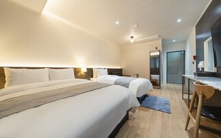 Quarto de hotel com duas camas, uma mesa, uma cadeira e um espelho.