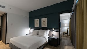 Quarto de hotel moderno com uma cama grande, mesas de cabeceira e obras de arte na parede.