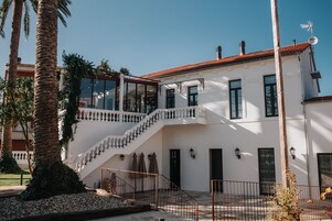 Um edifício branco com telhado de telhas vermelhas, uma escadaria e uma varanda.