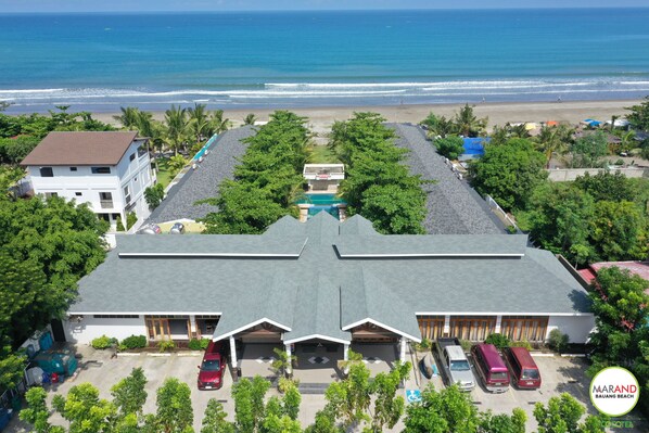 Um hotel com piscina, estacionamento e vista para a praia.