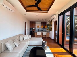 Uma sala moderna com um sofá, uma mesa de centro e uma área de jantar, com uma cozinha ao fundo.