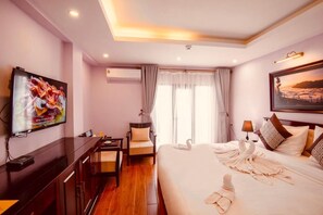 Quarto de hotel com cama, televisão, escrivaninha e cadeira.