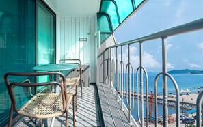 Varanda com mesa e cadeiras, vista para o mar e guarda-corpo.