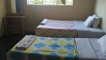 Quarto com duas camas, uma mesinha e janela com vista para o verde.
