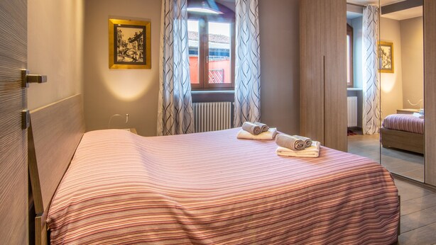Quarto moderno com cama grande, janela com cortinas, radiador e espelho.