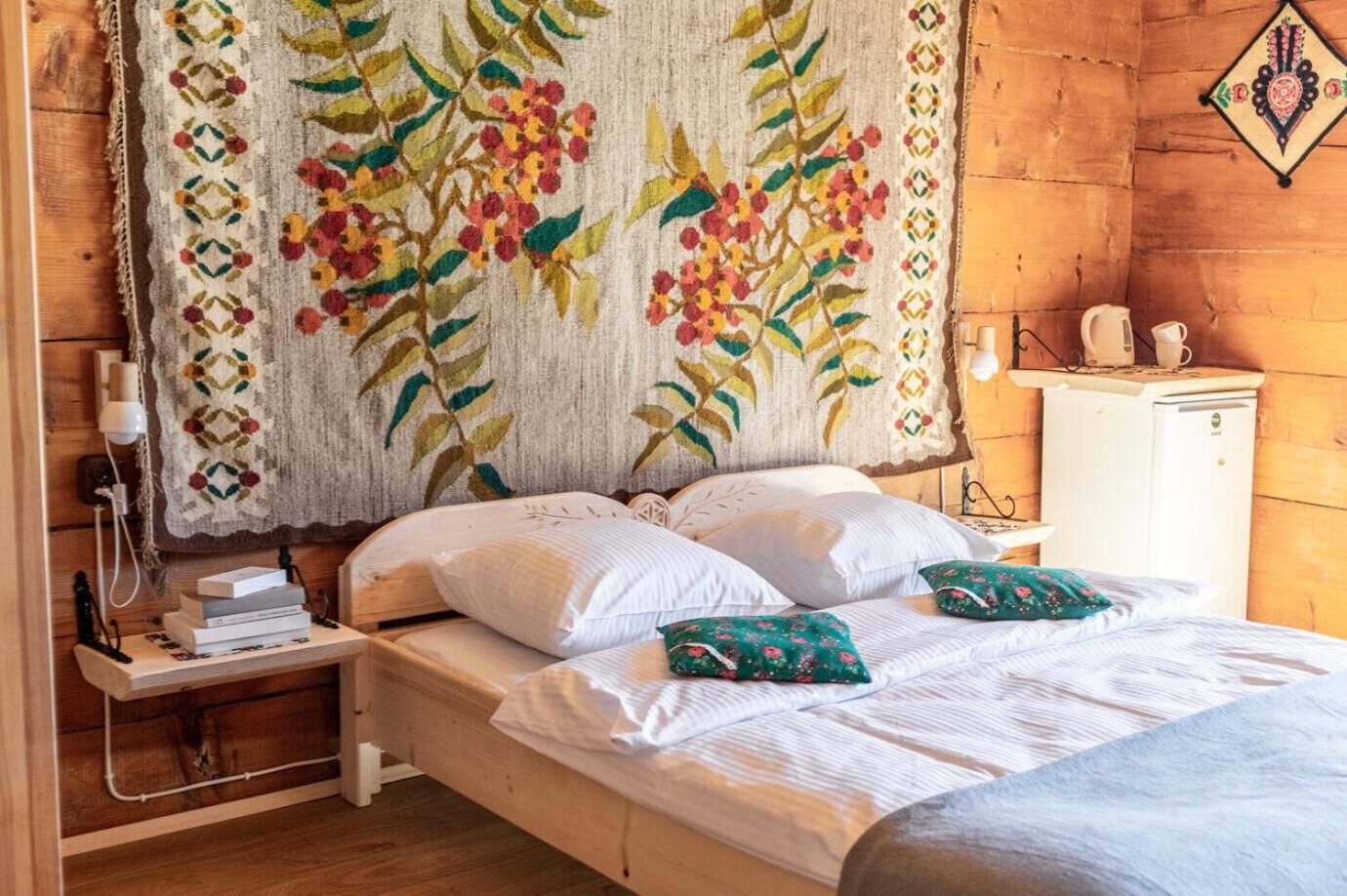 Um quarto aconchegante com uma cama, um criado-mudo, uma luminária e um pequeno armário branco.