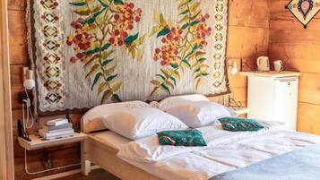 Um quarto aconchegante com uma cama, um criado-mudo, uma luminária e um pequeno armário branco.