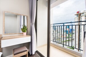 Apartamento moderno com varanda, um espelho grande, uma planta em vaso e vista para o horizonte urbano.