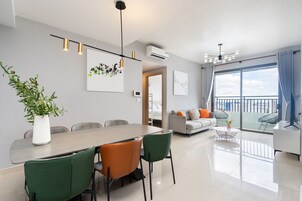 Uma sala de estar moderna com área de jantar, um conjunto de sofá e uma varanda com vista.