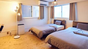 Quarto de hotel com duas camas, uma escrivaninha e um abajur.