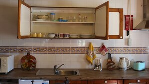 Cozinha com bancada de madeira, pia e prateleira sobre a pia.