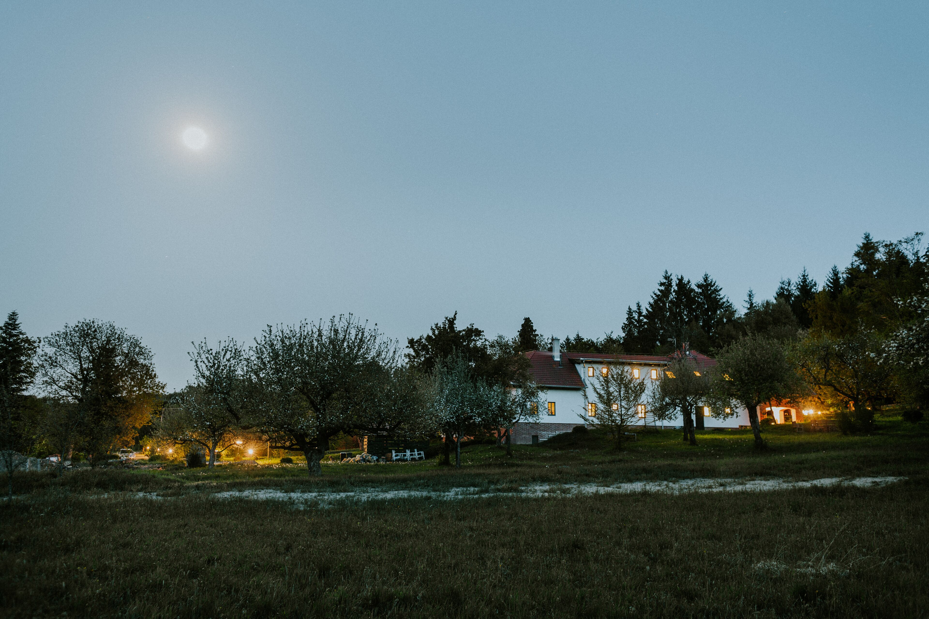 Uma casa com telhado vermelho, rodeada por árvores e um campo gramado.