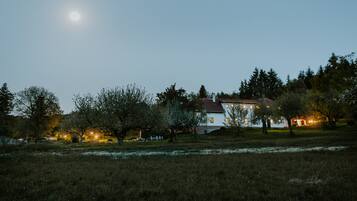 Uma casa com telhado vermelho, rodeada por árvores e um campo gramado.