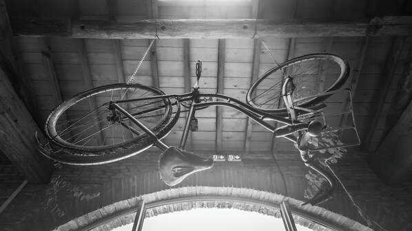 Uma bicicleta pendurada de cabeça para baixo em um quarto de madeira com parede de tijolos e janela.