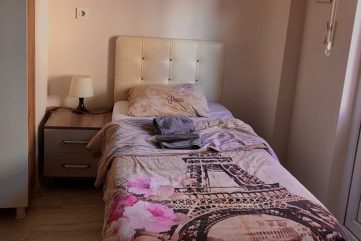 Quarto com cama, mesa de cabeceira com abajur e ar condicionado na parede.
