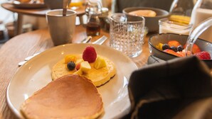 Uma mesa de café da manhã com panquecas, frutas e bebidas.
