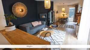 Uma sala de estar moderna com um sofá cinzento, mesa de centro de madeira e um espaço de refeições com mesa e cadeiras de madeira.