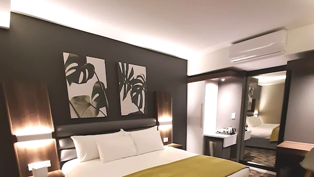 Quarto de hotel moderno com uma cama grande, uma mesa e um espelho.