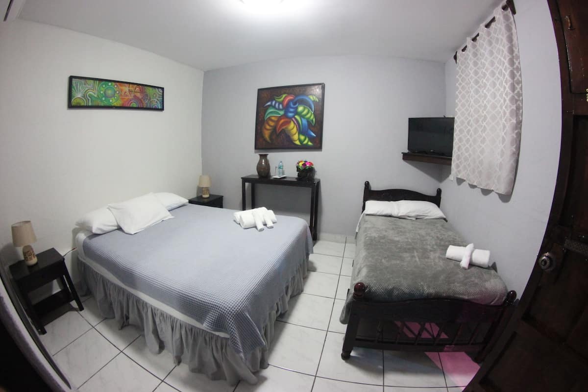 Quarto com duas camas, televisão e obras de arte nas paredes.