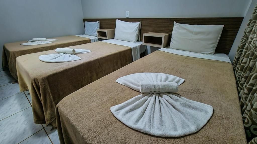 Quarto de hotel com duas camas de solteiro, cada uma com toalha e travesseiro.