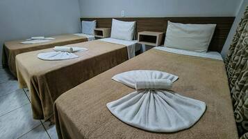 Quarto de hotel com duas camas de solteiro, cada uma com toalha e travesseiro.