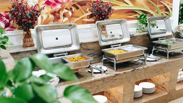 Disposição de buffet com várias estações de comida, bancada de mármore e um mural floral ao fundo.