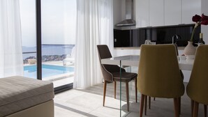Cozinha moderna com uma janela ampla, área de refeições com cadeiras amarelas e vista para o mar.