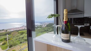 Uma garrafa de champanhe Moet & Chandon sobre uma bancada branca, com vista para a paisagem costeira através de uma janela.