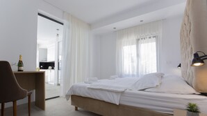 Quarto de hotel moderno com cama, escrivaninha e cadeira. Há uma garrafa de champanhe na escrivaninha.