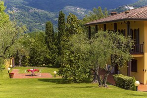 Uma villa com jardim, um alpendre com mesa e cadeiras, e vista para as colinas ao redor.