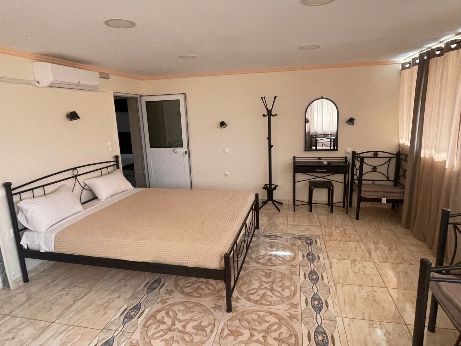 Quarto com cama, escrivaninha, cadeira, espelho e porta.