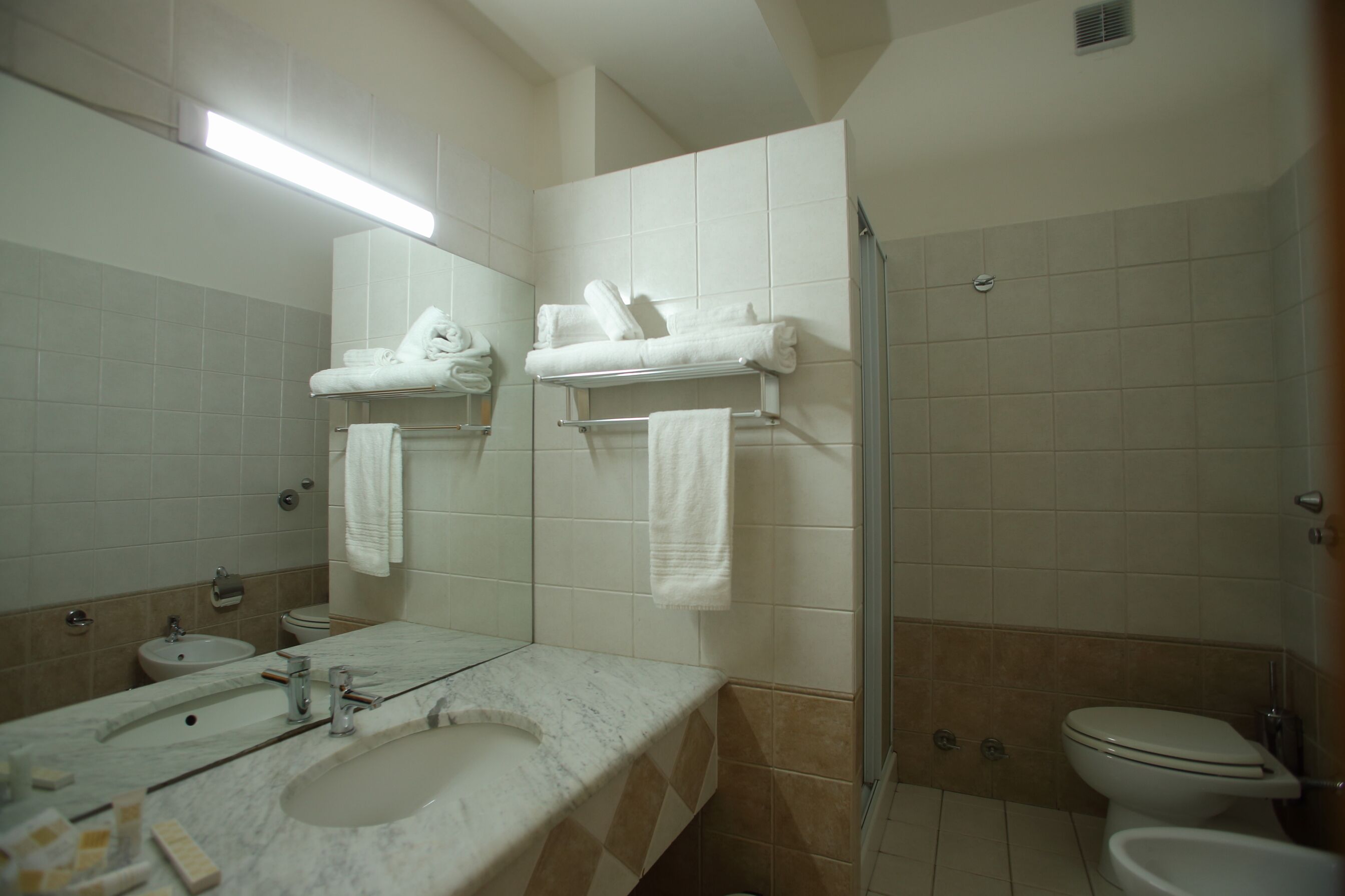 Casa de banho com lavatório, espelho, porta-toalhas e sanita.