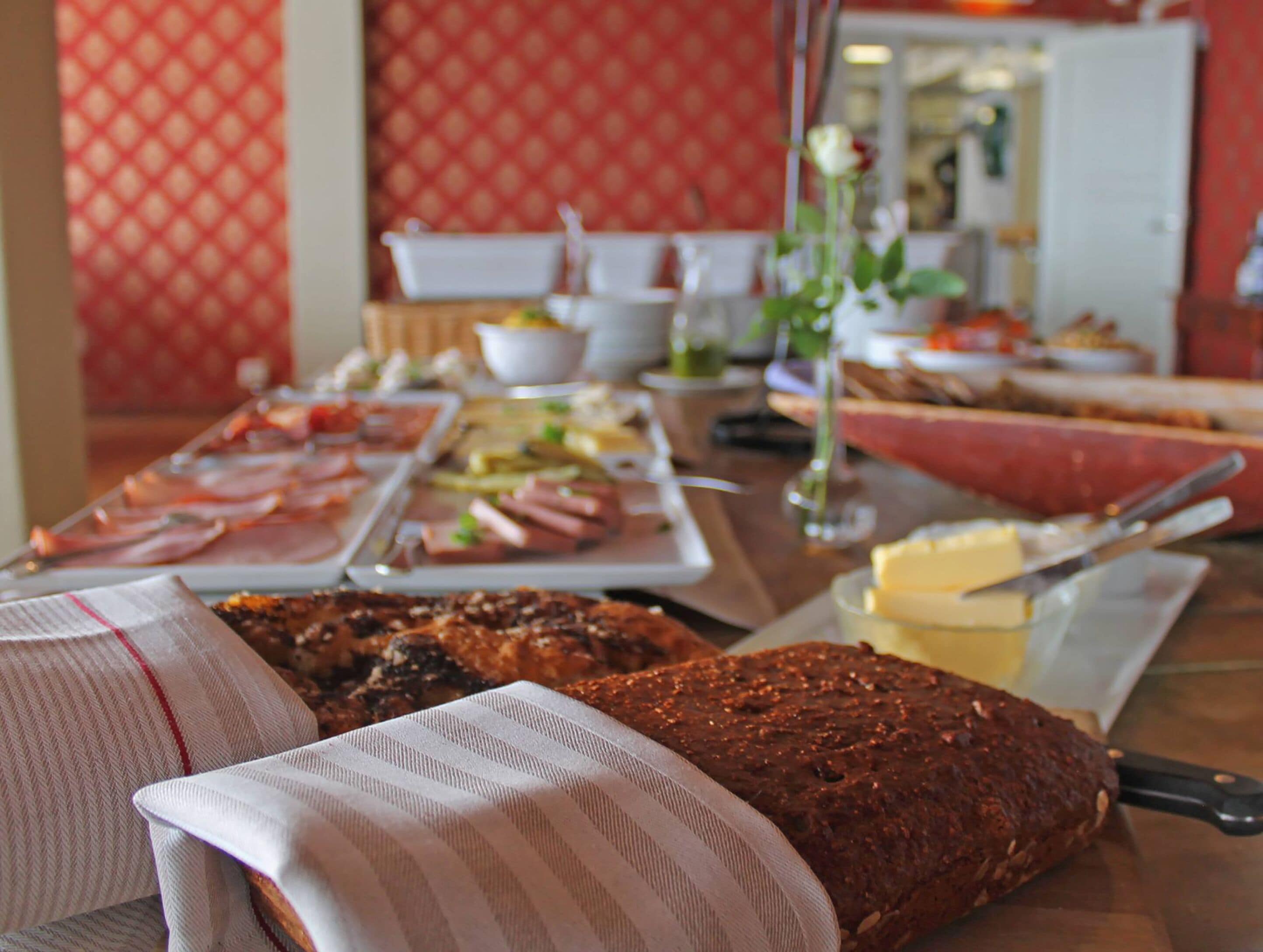 Mesa de buffet com diversos alimentos, incluindo carnes, queijos e pães.