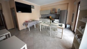 Uma cozinha moderna com armários brancos, uma mesa de jantar com cadeiras e forno embutido.