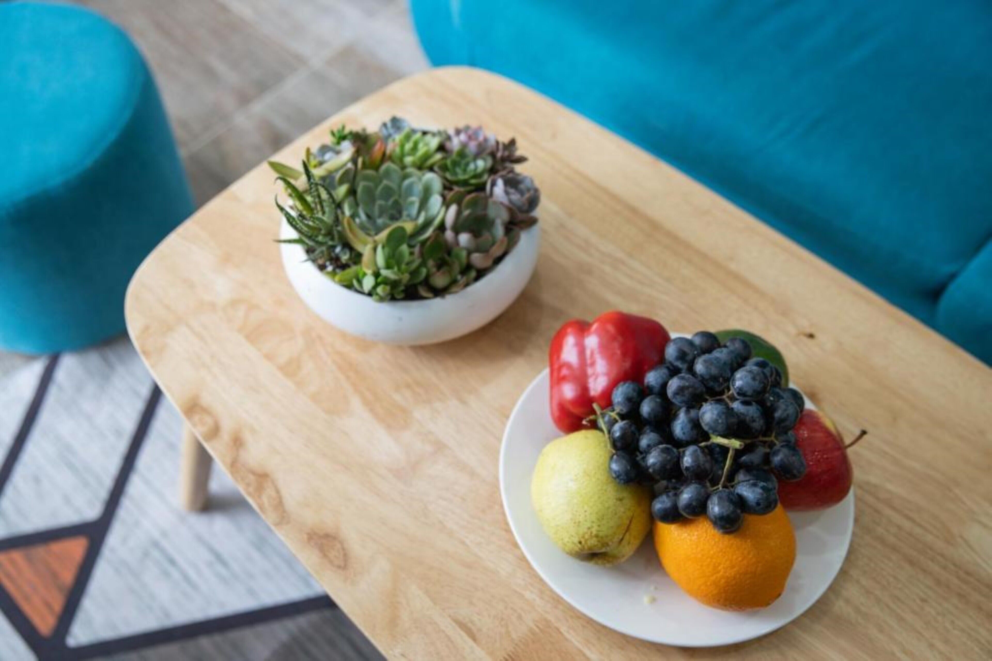 Uma mesa de madeira com uma tigela de suculentas e uma travessa de frutas.