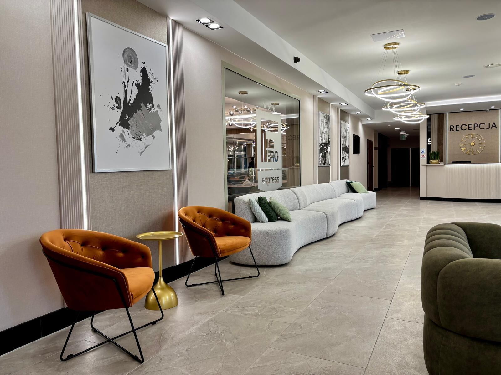 Um lobby moderno com balcão de recepção, área de estar e obras de arte nas paredes.