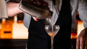 Um bartender a servir uma bebida num copo de martini.