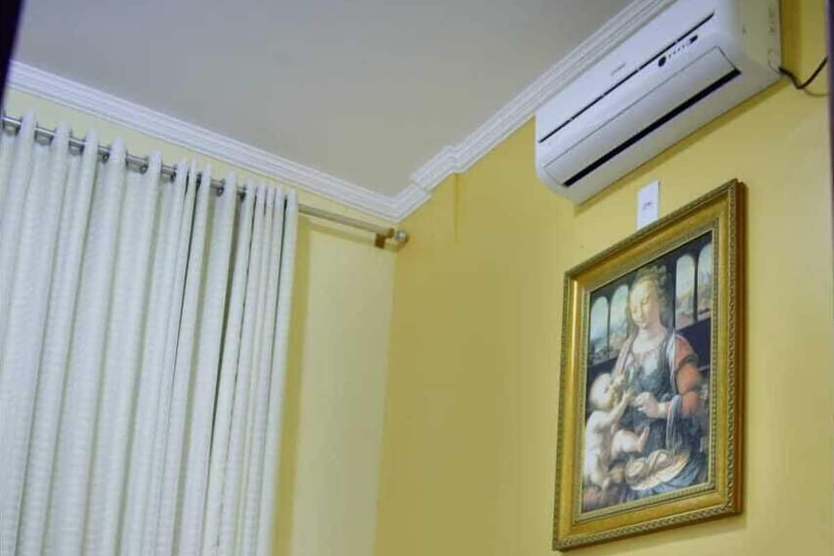Quarto de hotel com uma cama, um quadro na parede e um aparelho de ar condicionado.