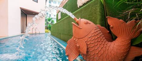 Piscina com escultura decorativa de peixe e água jorrando da boca.