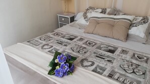 Cama bem arrumada com colcha estampada e um buquê de flores sobre ela.