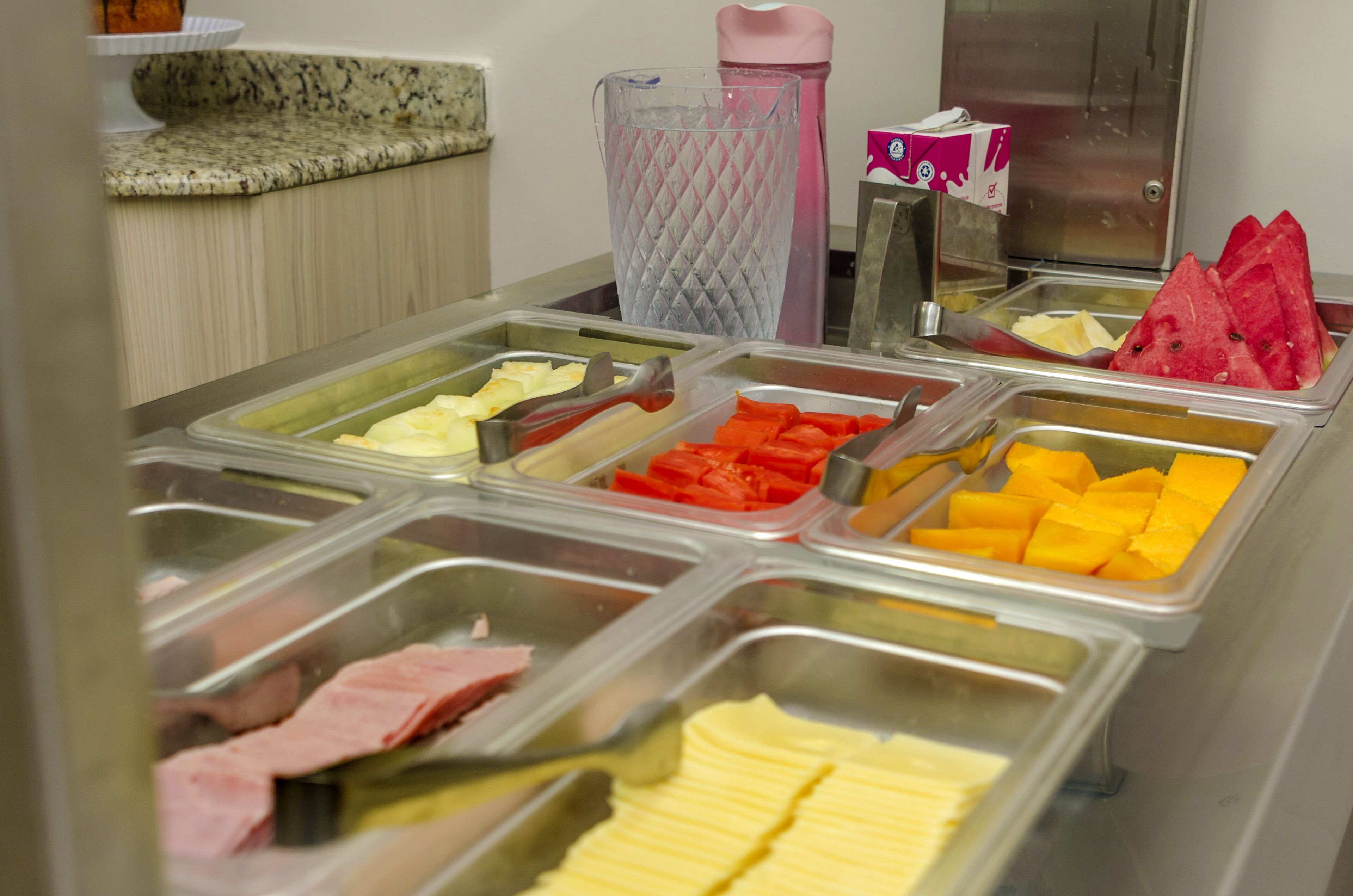 Buffet com diversos alimentos, incluindo carnes, queijos e frutas.