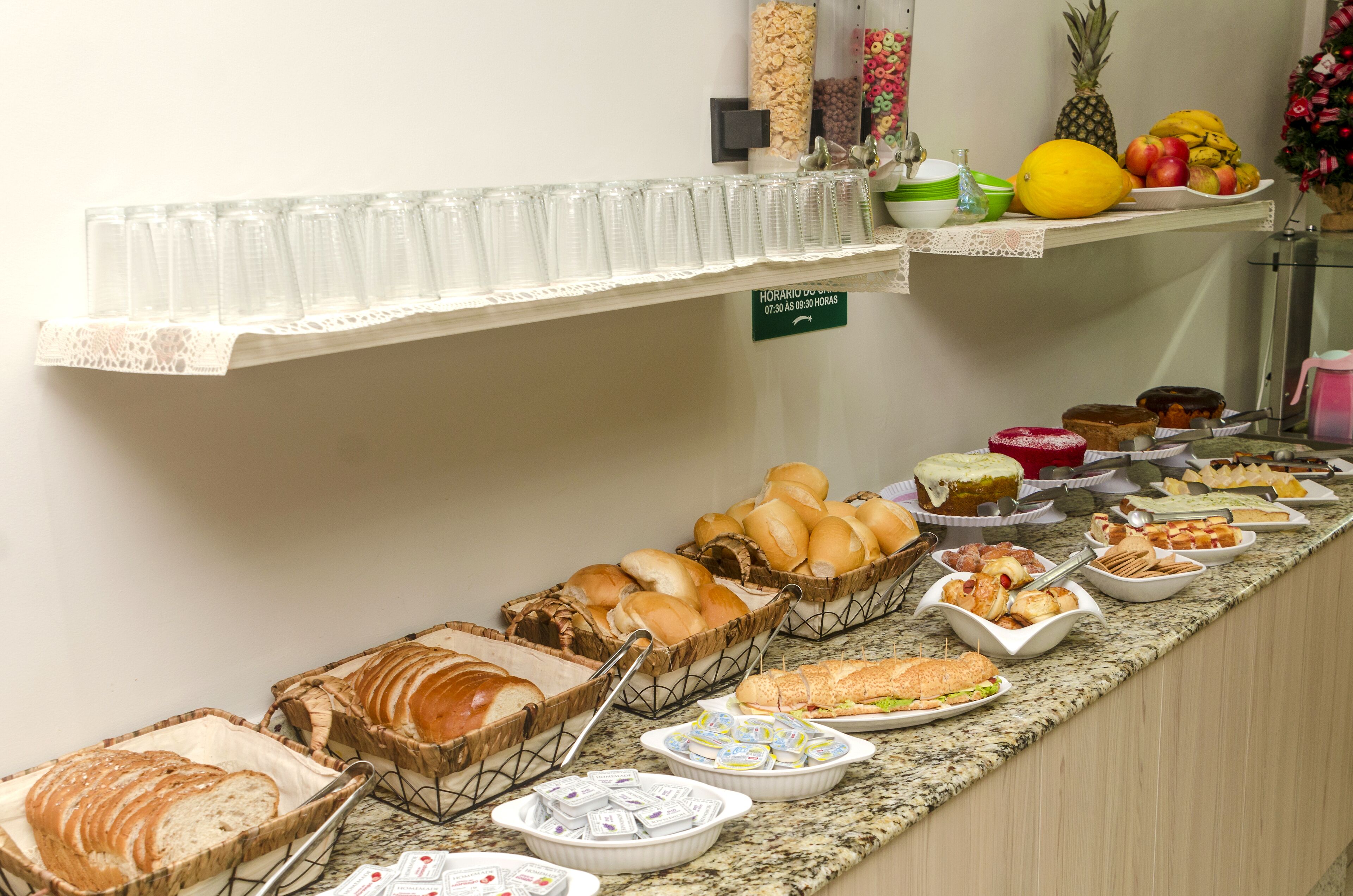 Buffet com diversos alimentos, incluindo pão, doces e frutas.