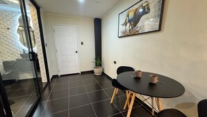 Uma cozinha moderna com piso de azulejos escuros, uma porta branca e um vaso com planta.